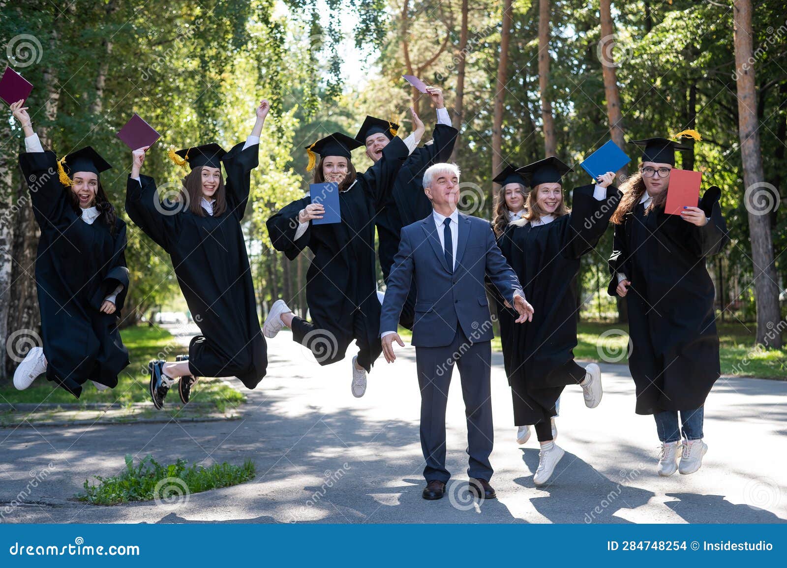 A University Professor and Seven Robed Graduates are Jumping Outdoors ...