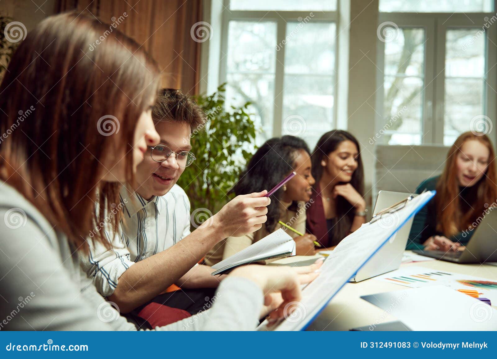 University Students Sitting Together at Table with Books and Laptops ...