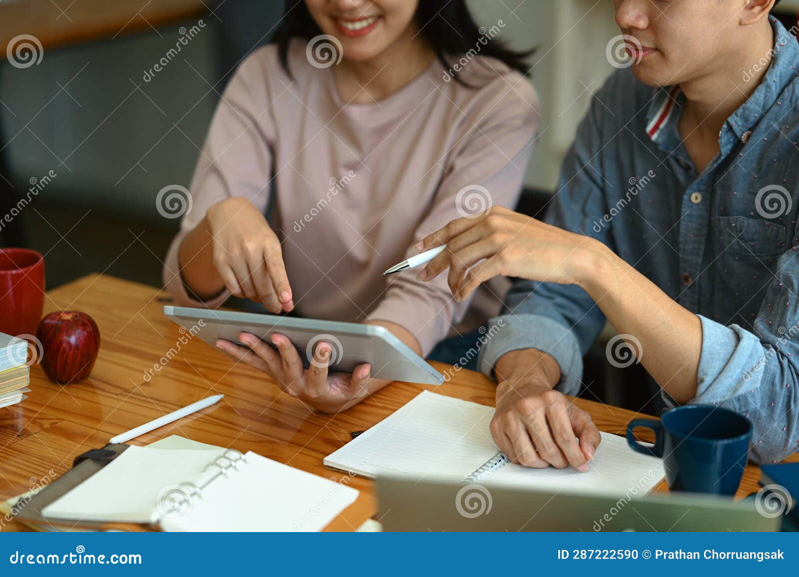 University Students Using Digital Tablet, Collaborating on a Project in ...