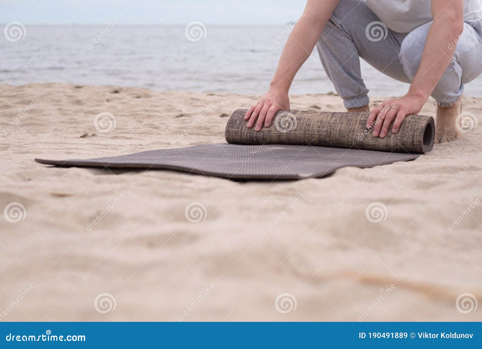 Man Rolling Up Yoga Mat after Training on Sandy Beach Stock Image ...