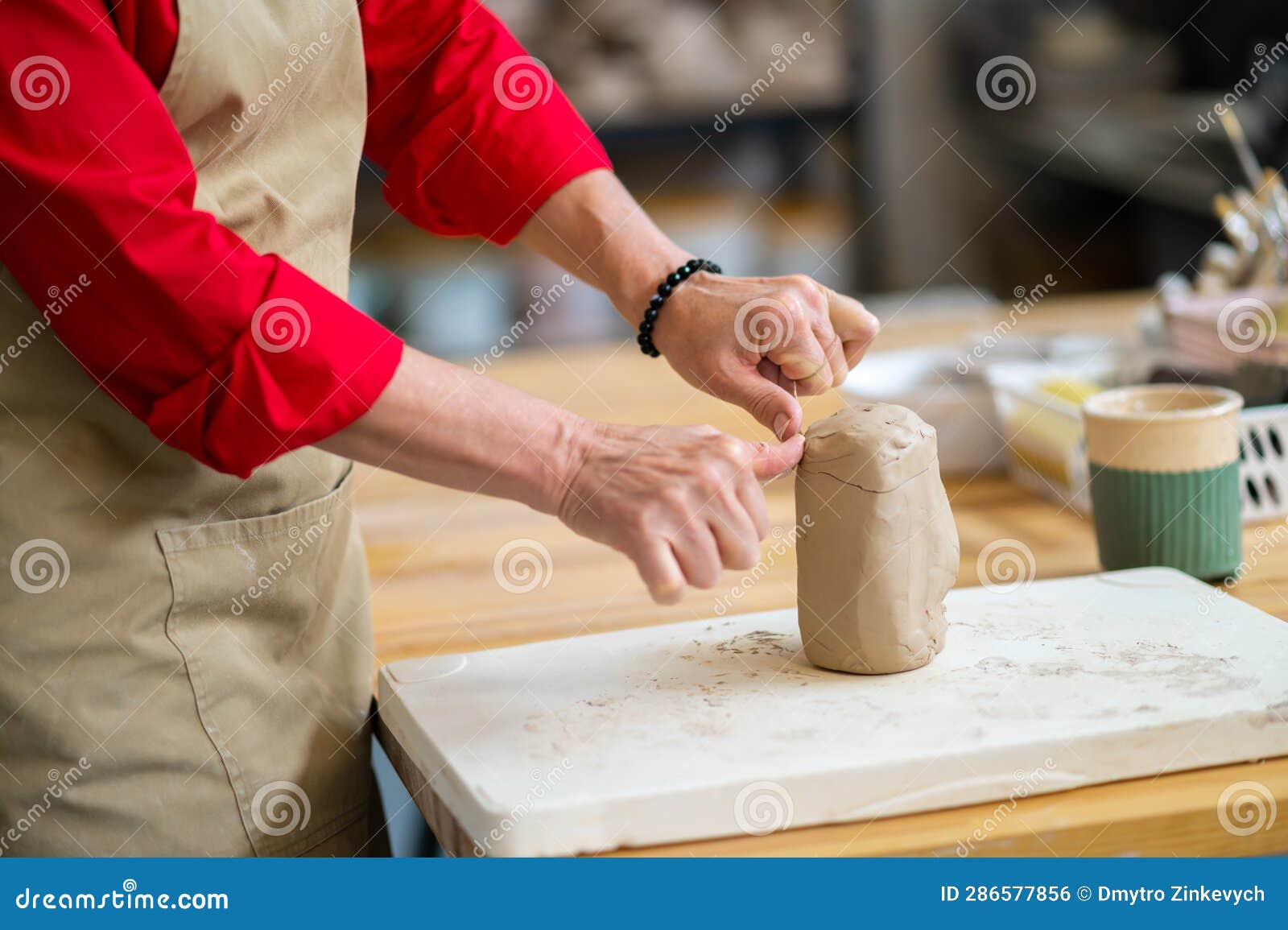 Unrecognizable Woman Cutting Clay with Thread Standing Behind Table in ...