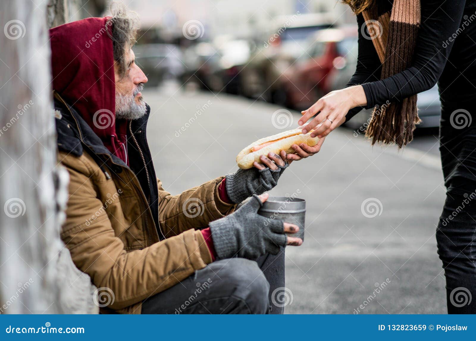 Unrecognizable Woman Giving Food To Homeless Beggar Man Sitting In City