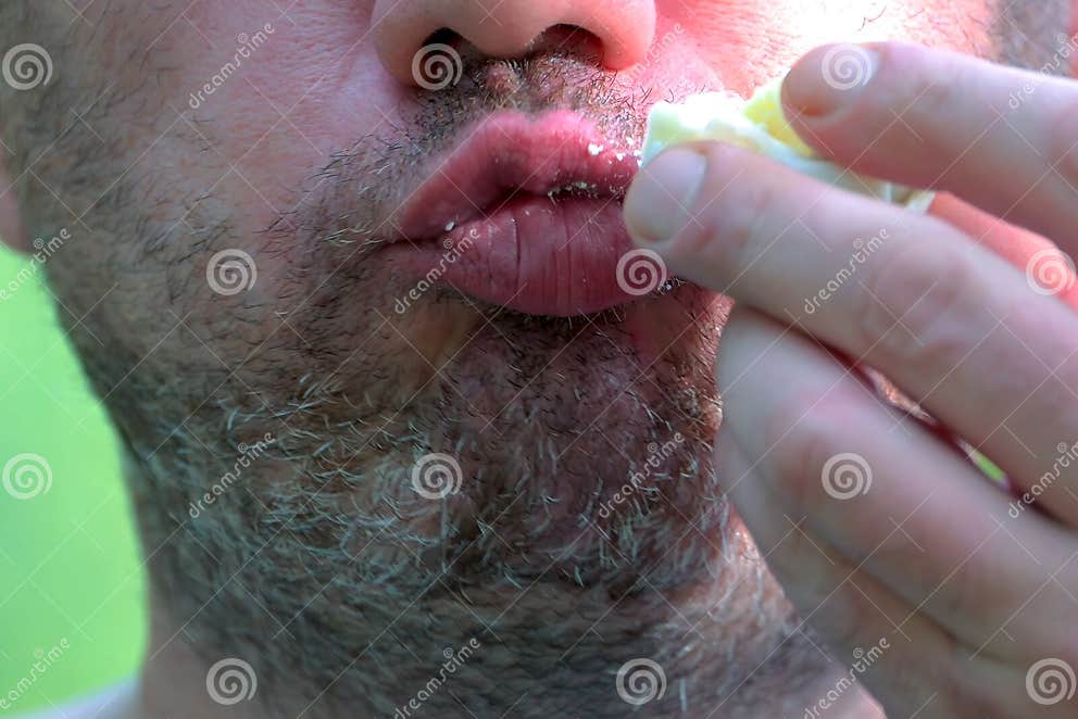 An Unshaven Man With A Beard Eats A Boiled Egg Against The Background Of Green Nature Stock