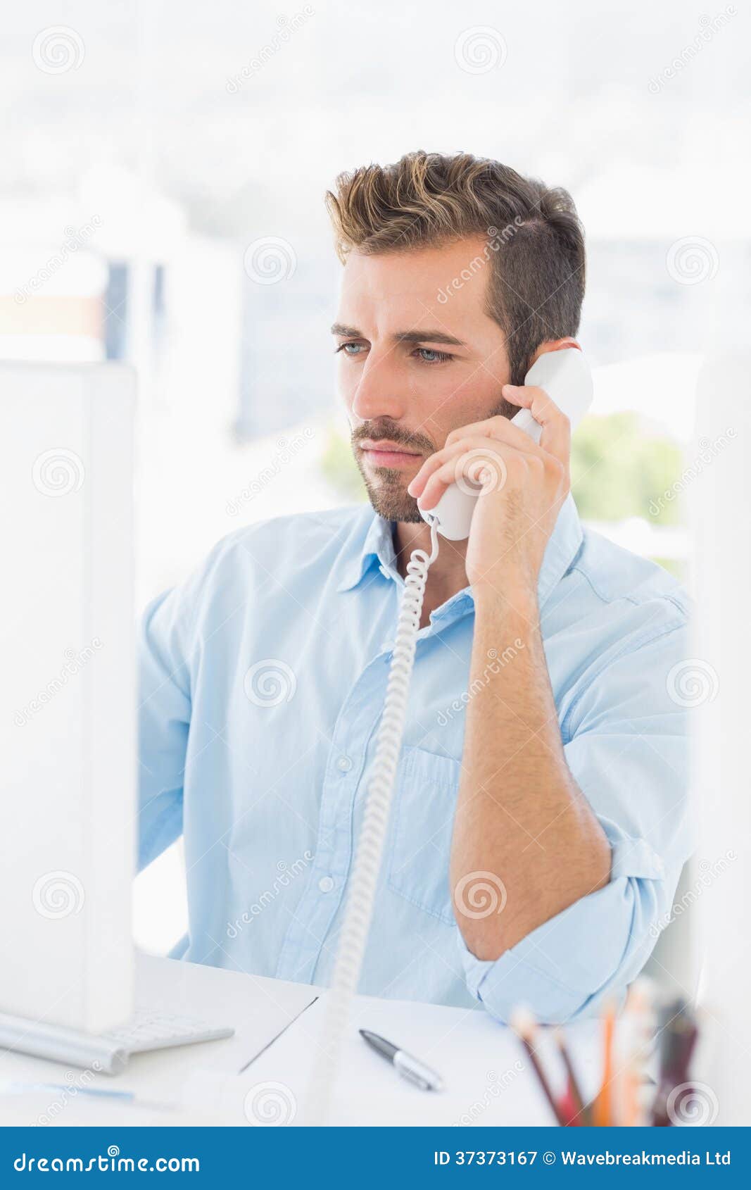 Uomo Serio Che Utilizza Telefono E Computer Nell'ufficio Immagine Stock ...