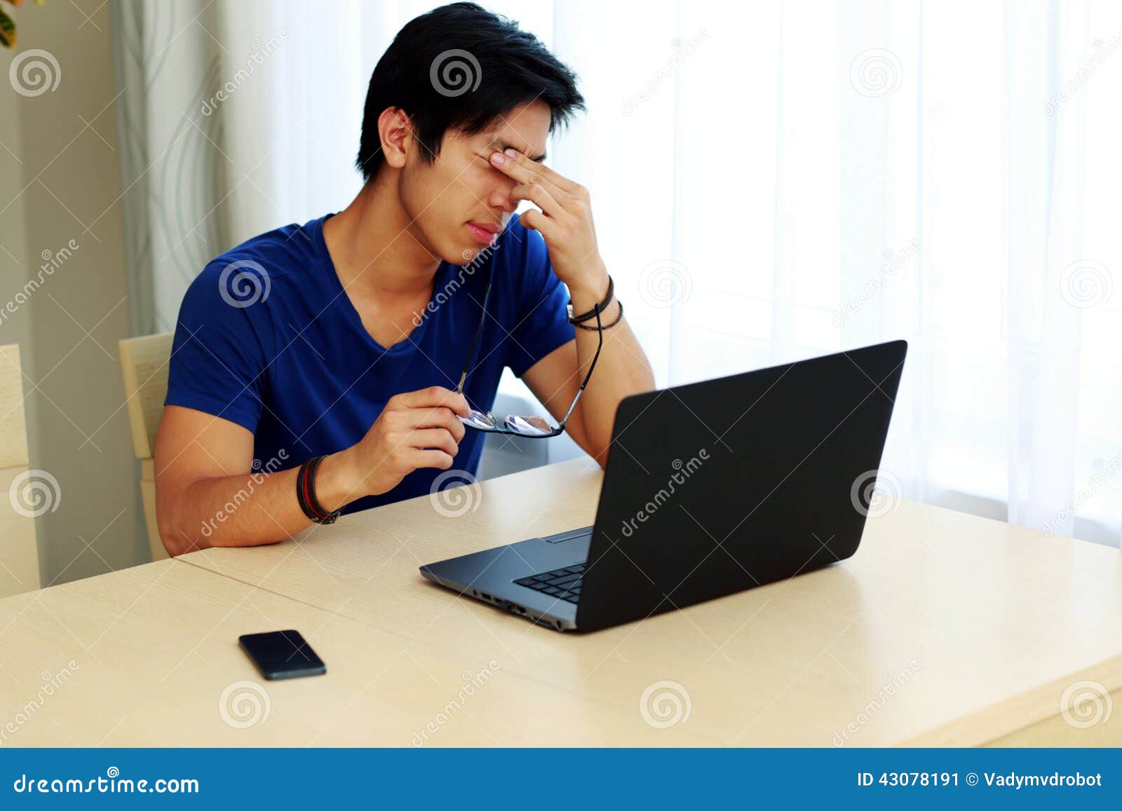 Uomo Stanco Che Si Siede Alla Tavola Con Il Computer Portatile Immagine ...