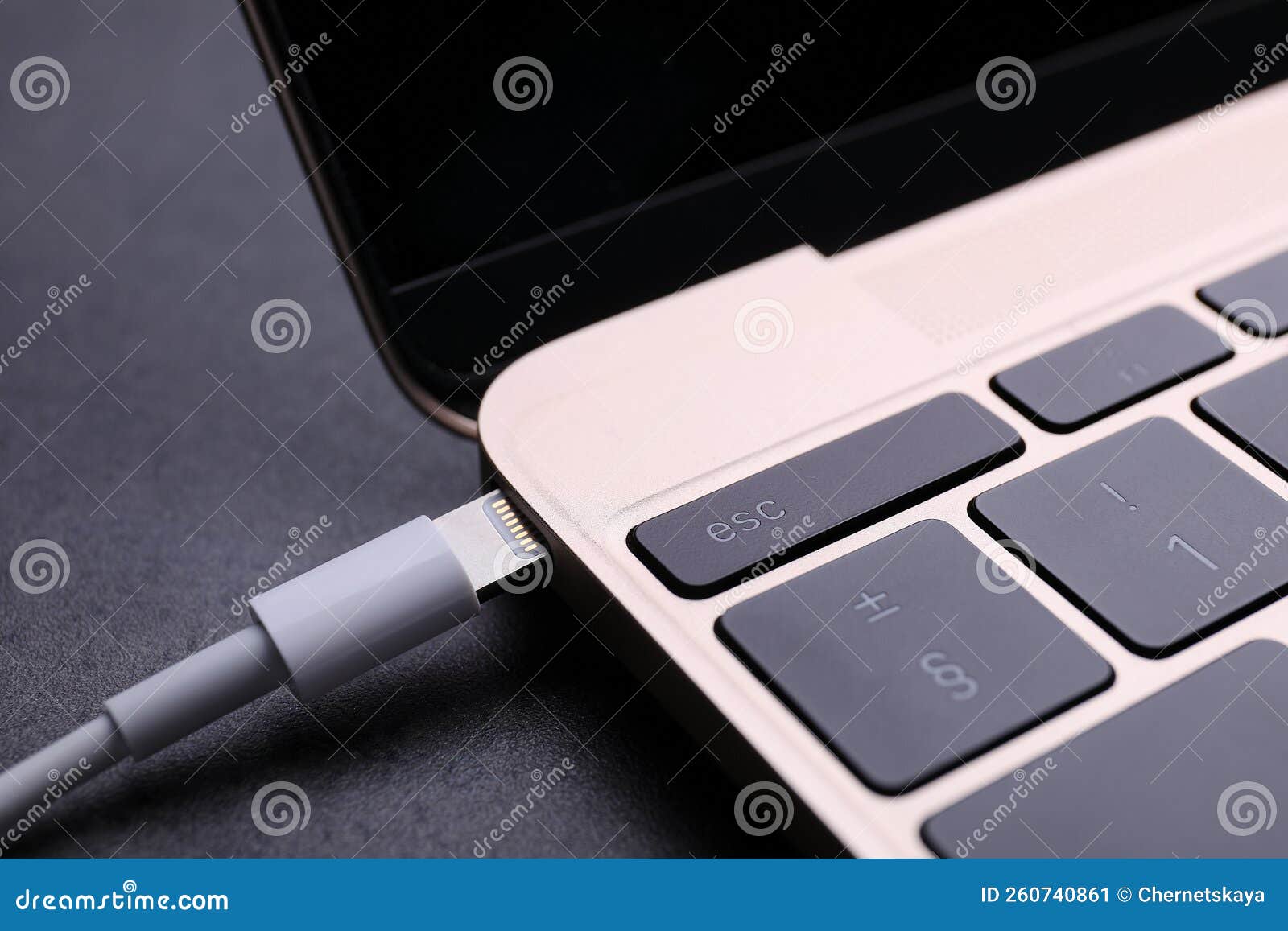 USB Cable with Lightning Connector and Laptop on Black Table, Closeup ...