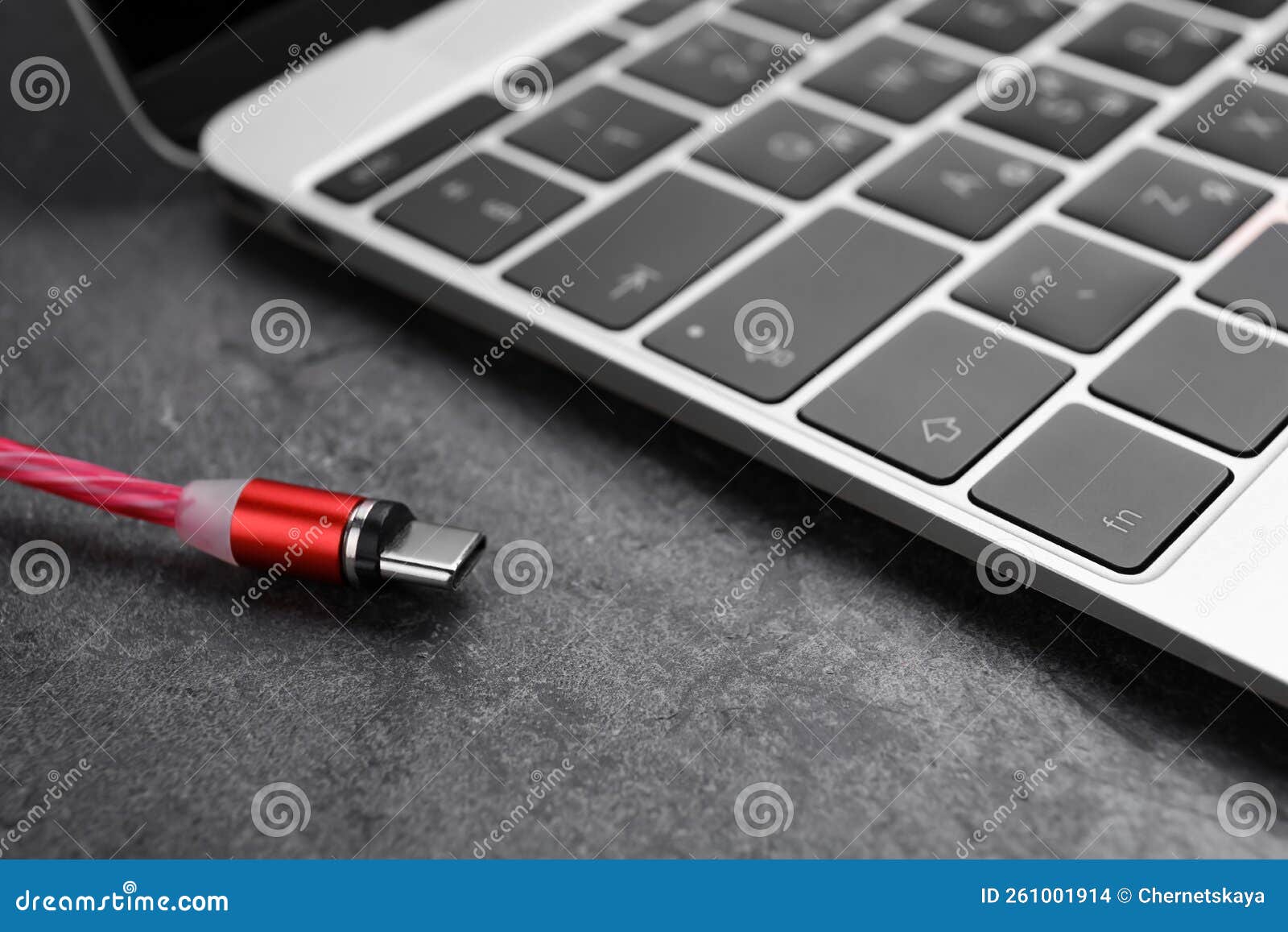 USB Cable with Type C Connector and Laptop on Grey Table, Closeup Stock ...