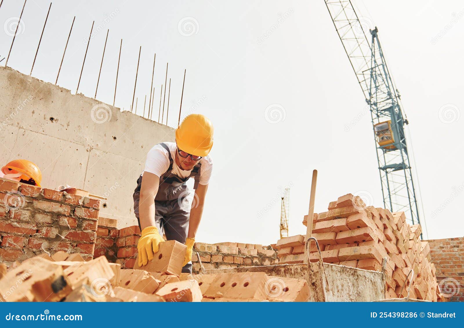 Using Bricks. Young Construction Worker in Uniform is Busy at the ...