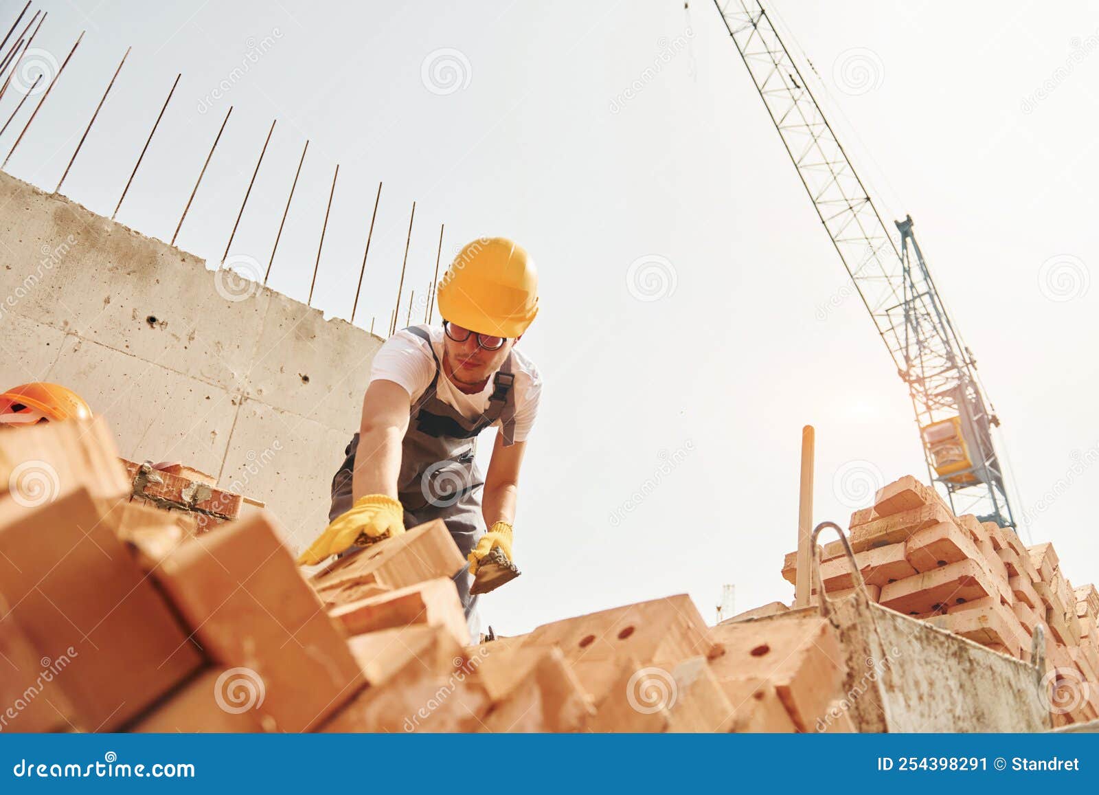 Using Bricks. Young Construction Worker in Uniform is Busy at the ...