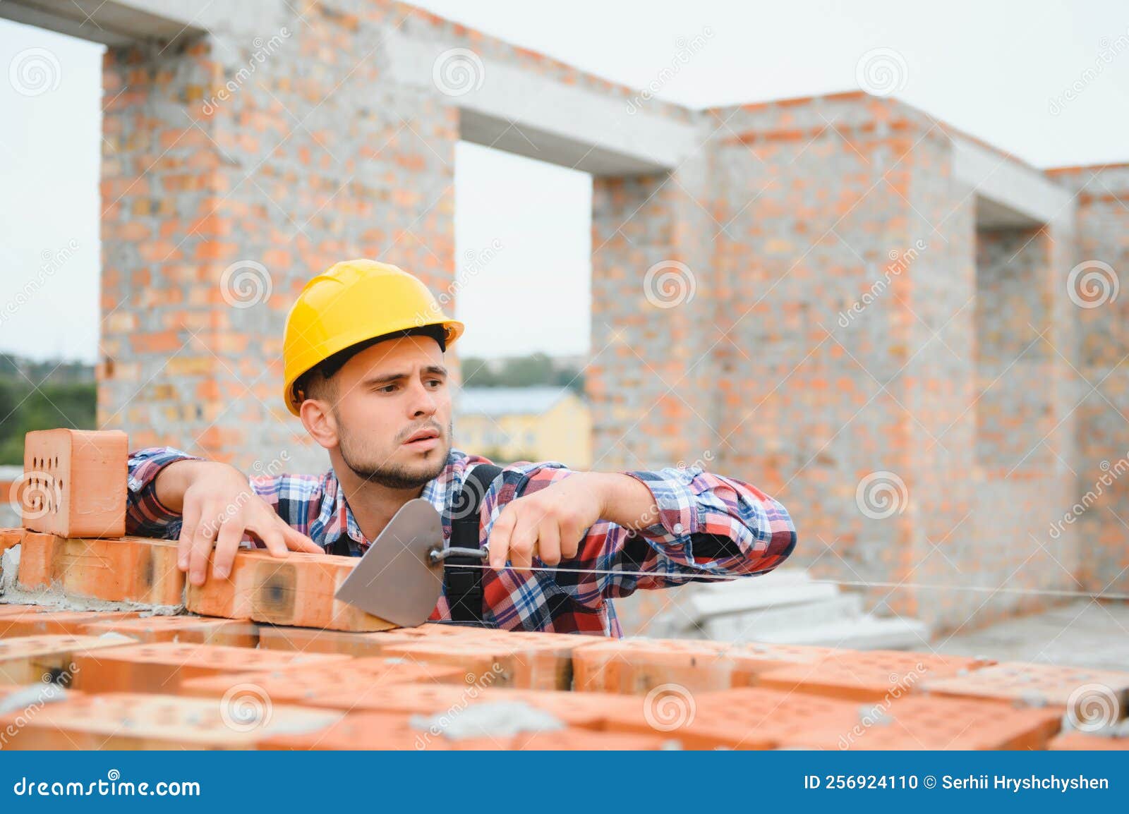 Using Bricks. Young Construction Worker in Uniform is Busy at the ...