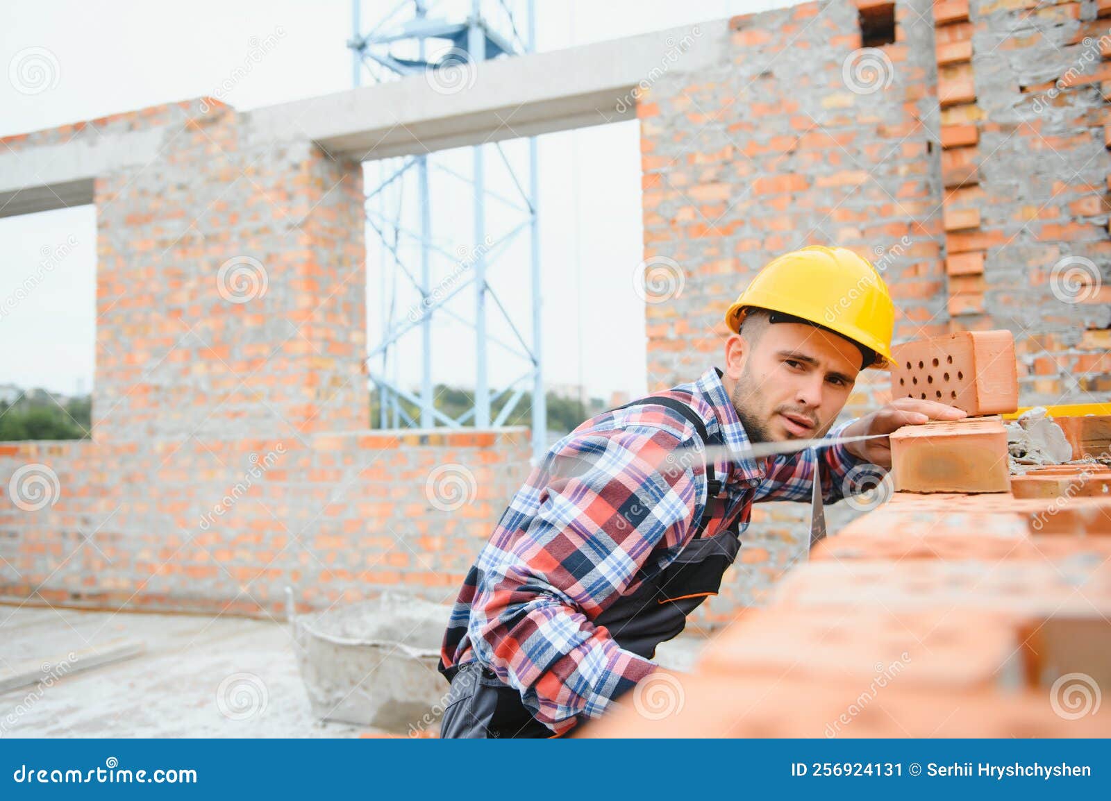 Using Bricks. Young Construction Worker in Uniform is Busy at the ...