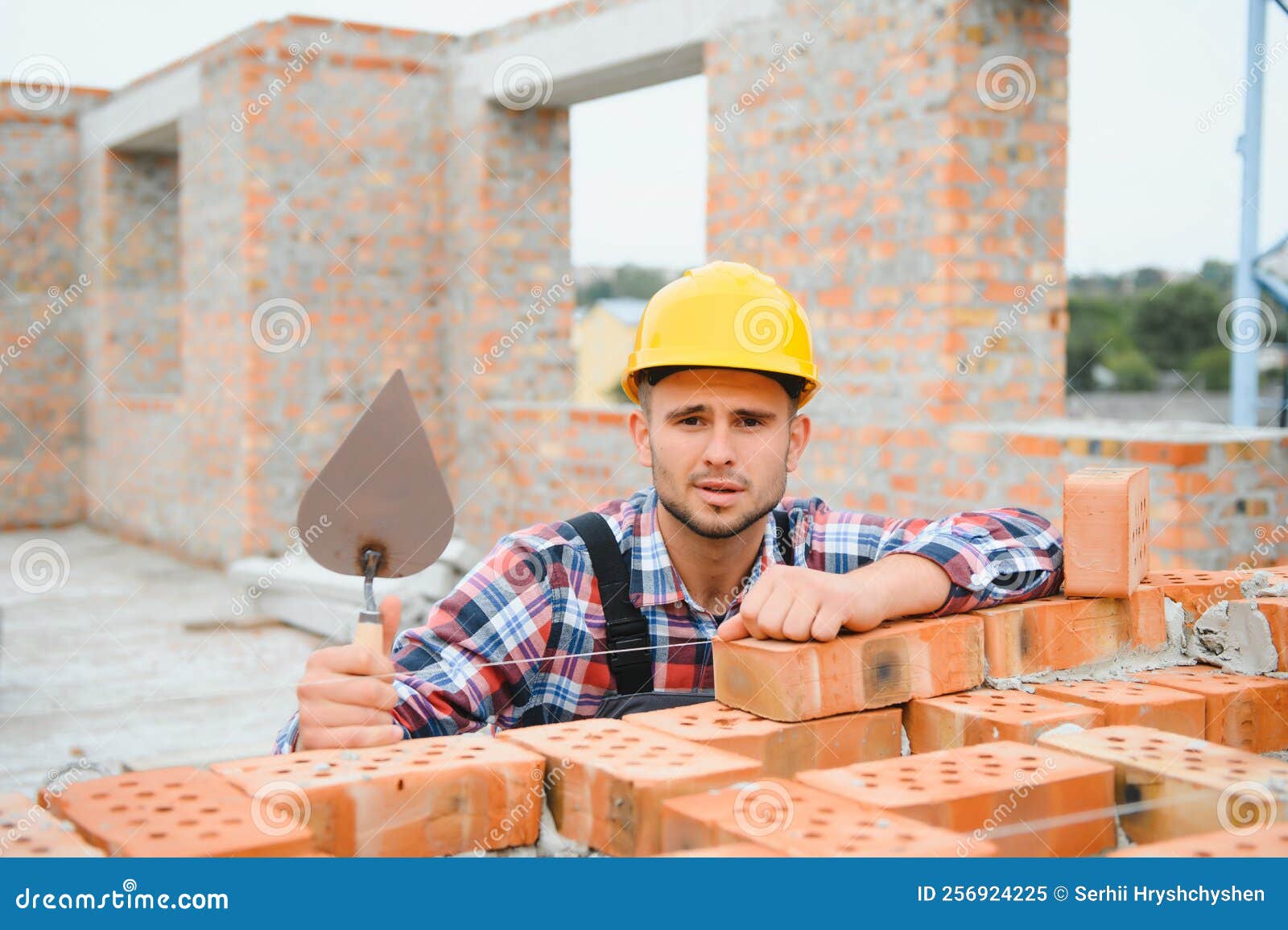 Using Bricks. Young Construction Worker in Uniform is Busy at the ...