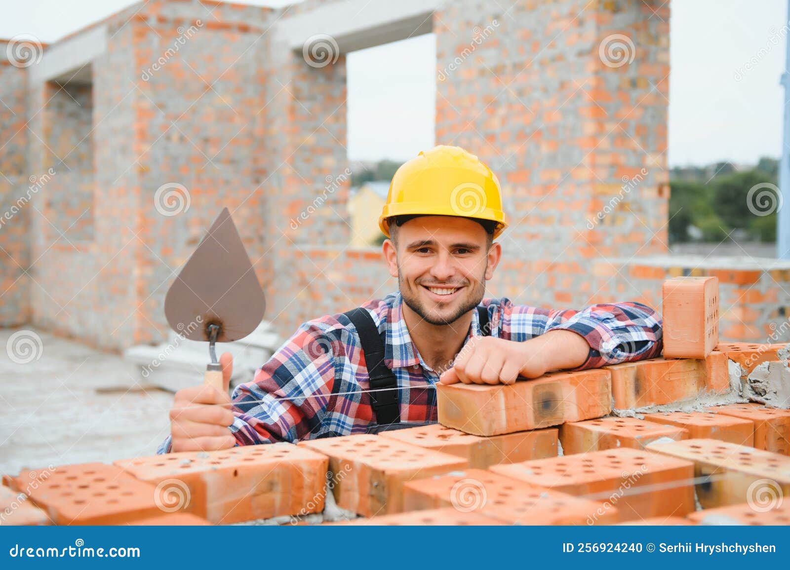 Using Bricks. Young Construction Worker in Uniform is Busy at the ...