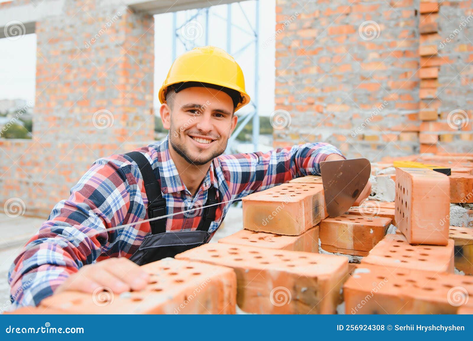 Using Bricks. Young Construction Worker in Uniform is Busy at the ...