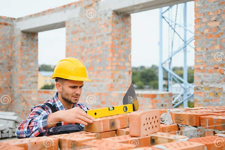 Using Bricks. Young Construction Worker in Uniform is Busy at the ...