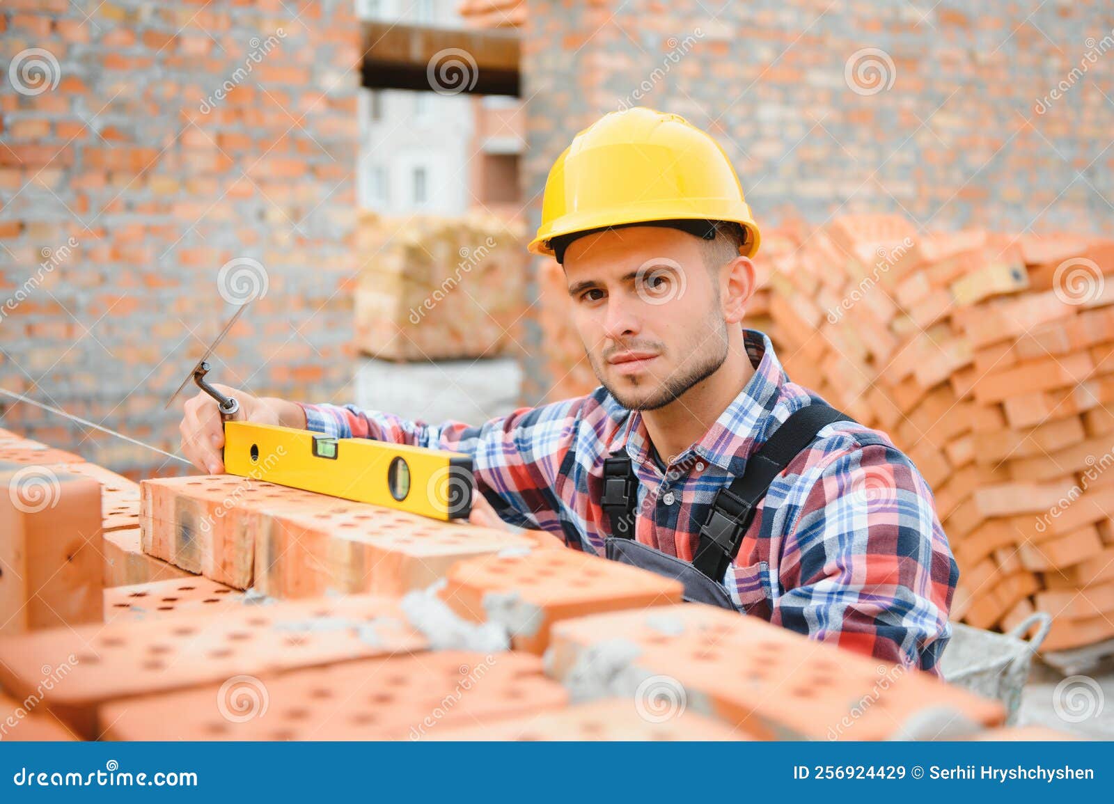 Using Bricks. Young Construction Worker in Uniform is Busy at the ...