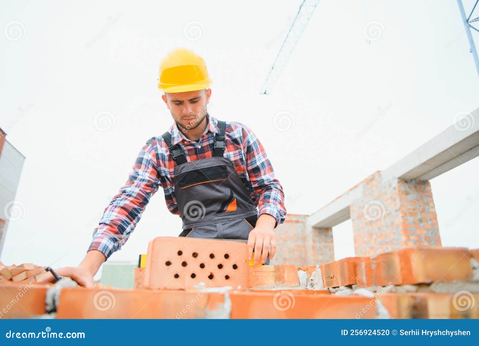 Using Bricks. Young Construction Worker in Uniform is Busy at the ...