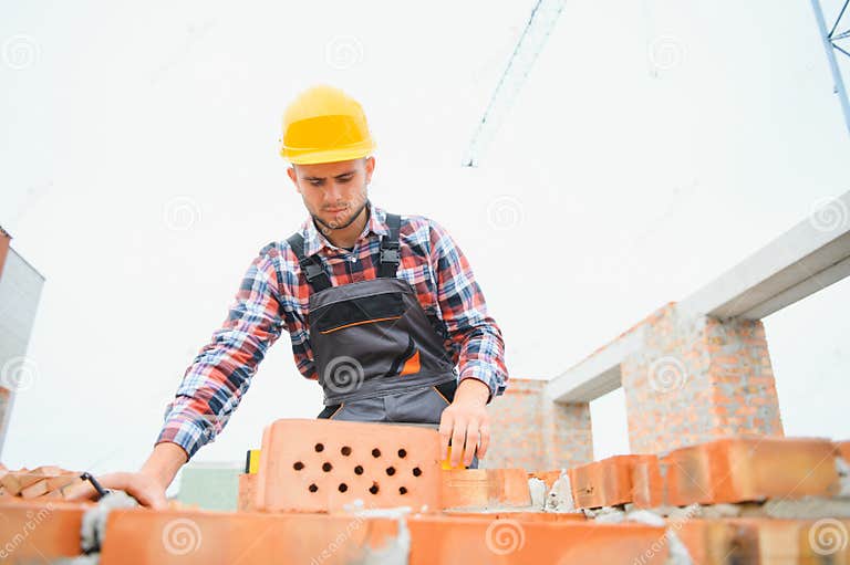 Using Bricks. Young Construction Worker in Uniform is Busy at the ...