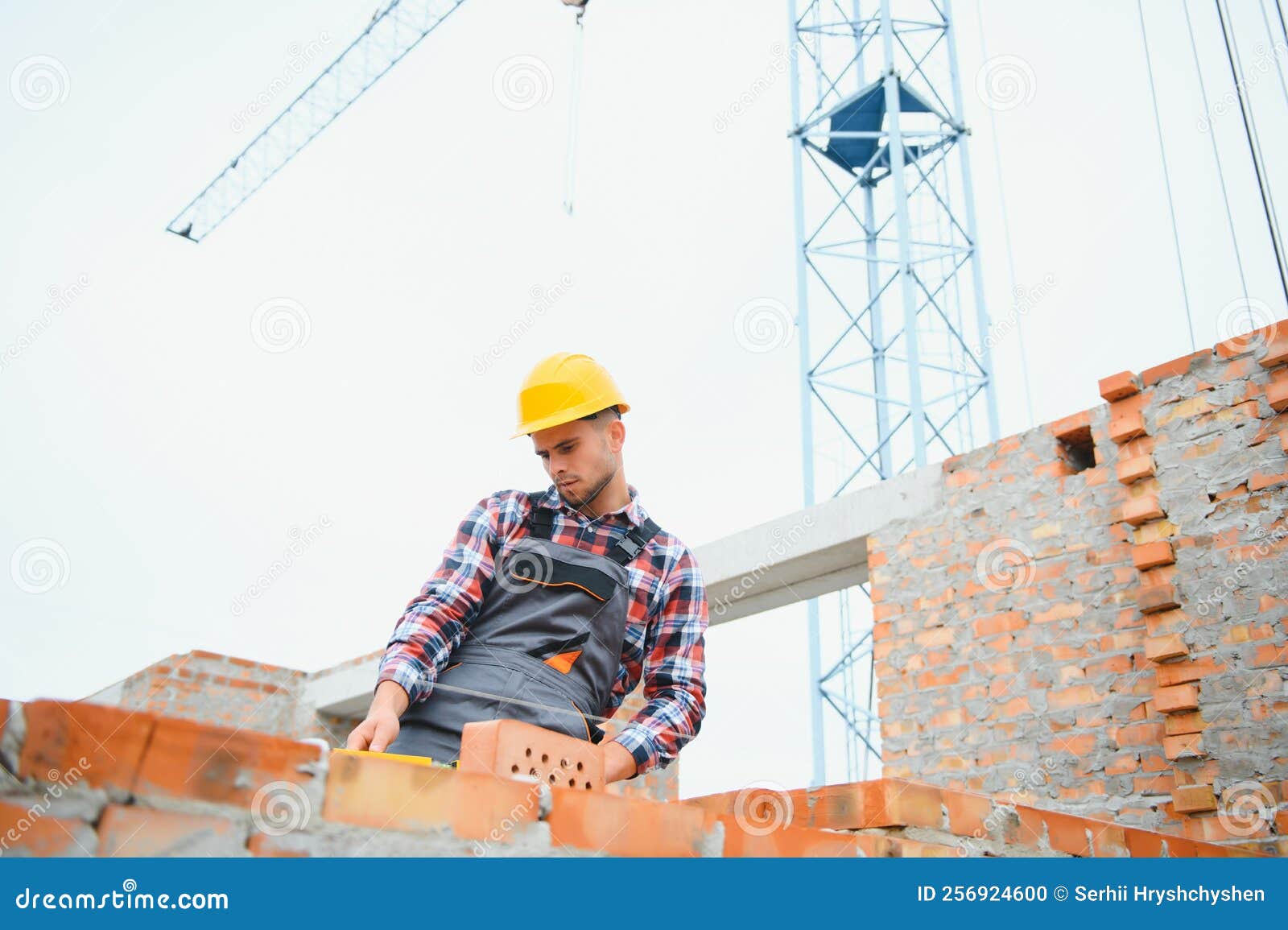 Using Bricks. Young Construction Worker in Uniform is Busy at the ...
