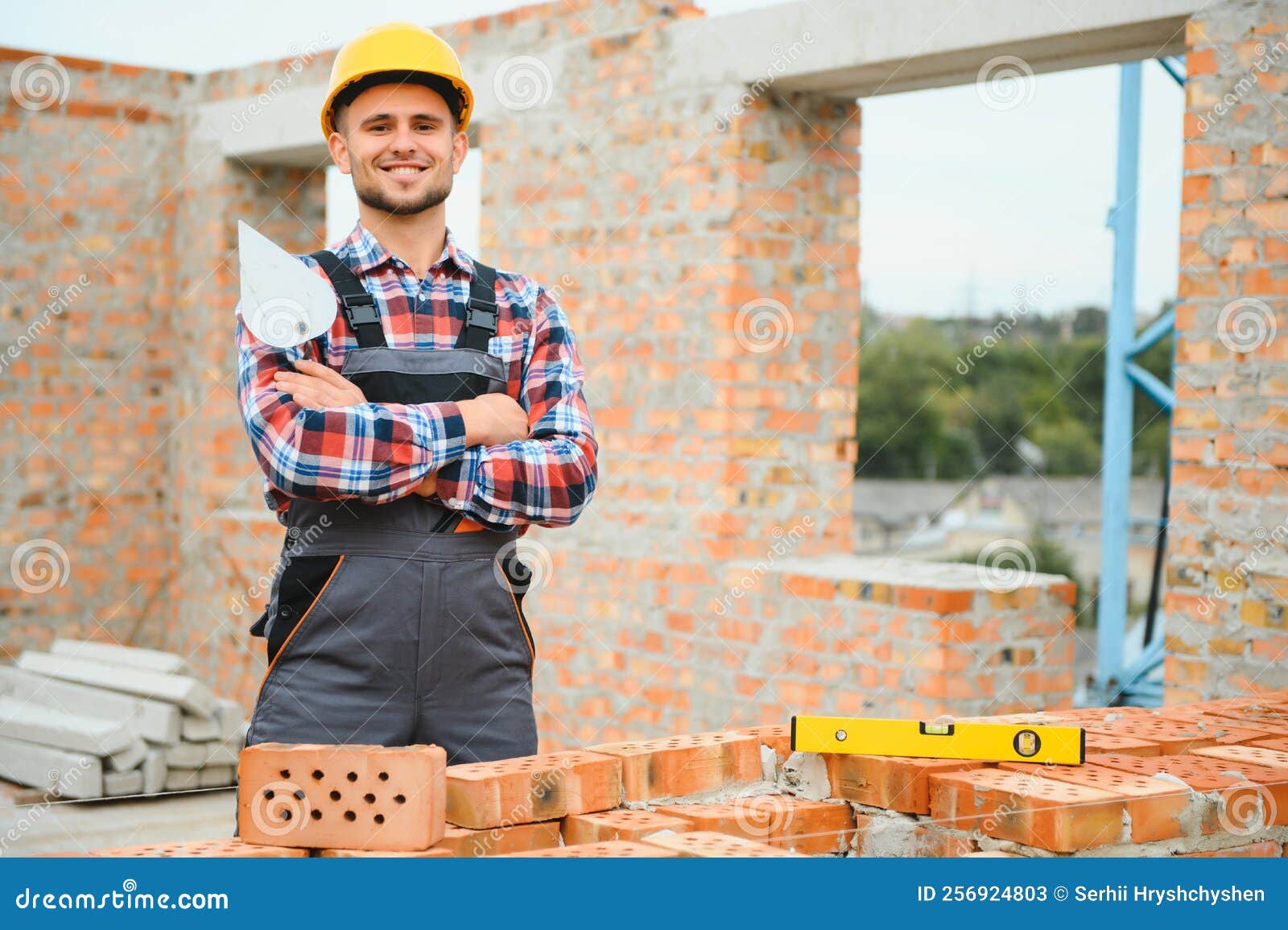 Using Bricks. Young Construction Worker in Uniform is Busy at the ...