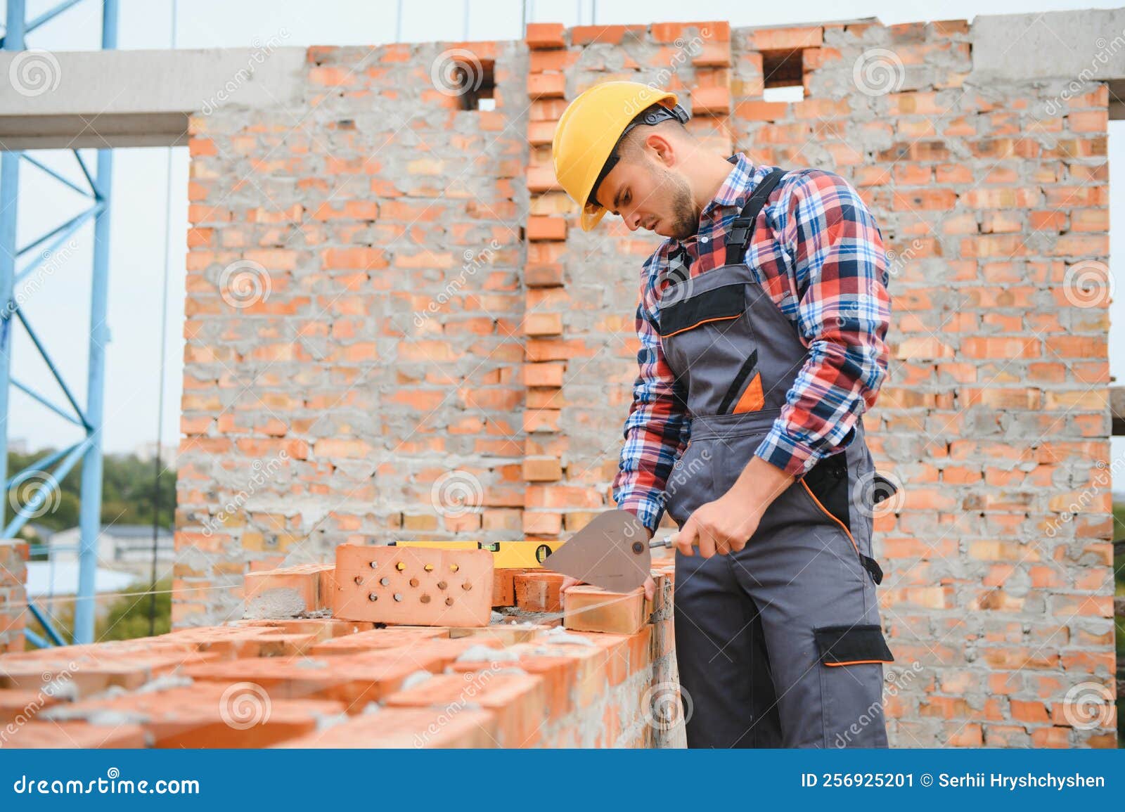 Using Bricks. Young Construction Worker in Uniform is Busy at the ...