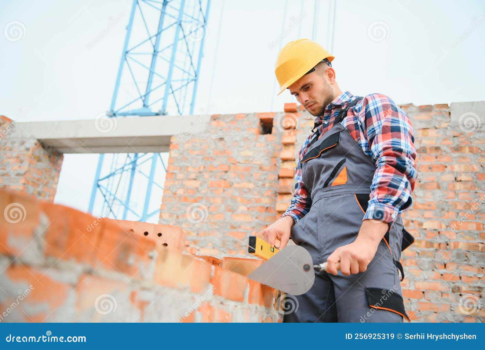 Using Bricks. Young Construction Worker in Uniform is Busy at the ...