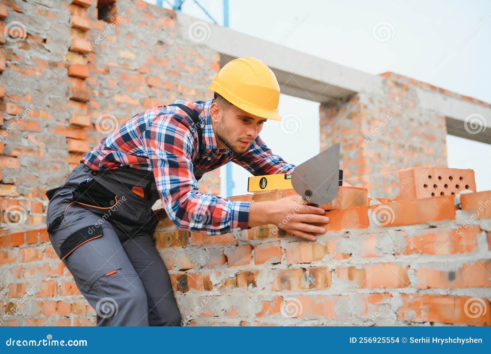 Using Bricks. Young Construction Worker in Uniform is Busy at the ...