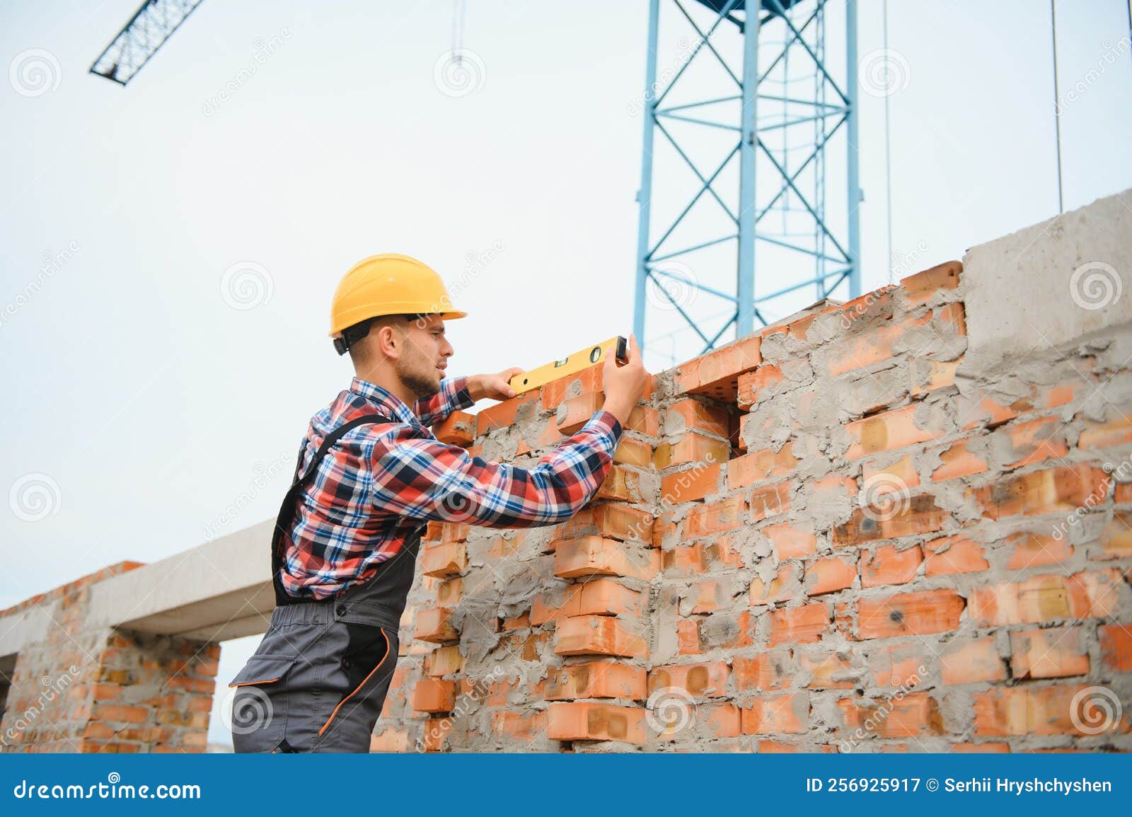 Using Bricks. Young Construction Worker in Uniform is Busy at the ...