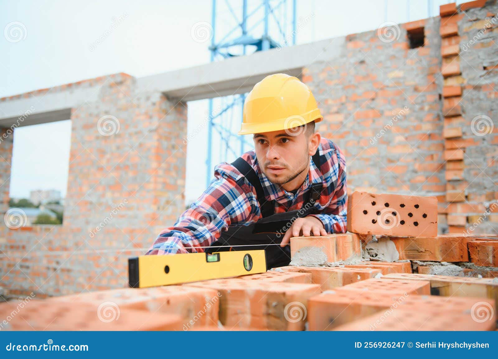 Using Bricks. Young Construction Worker in Uniform is Busy at the ...