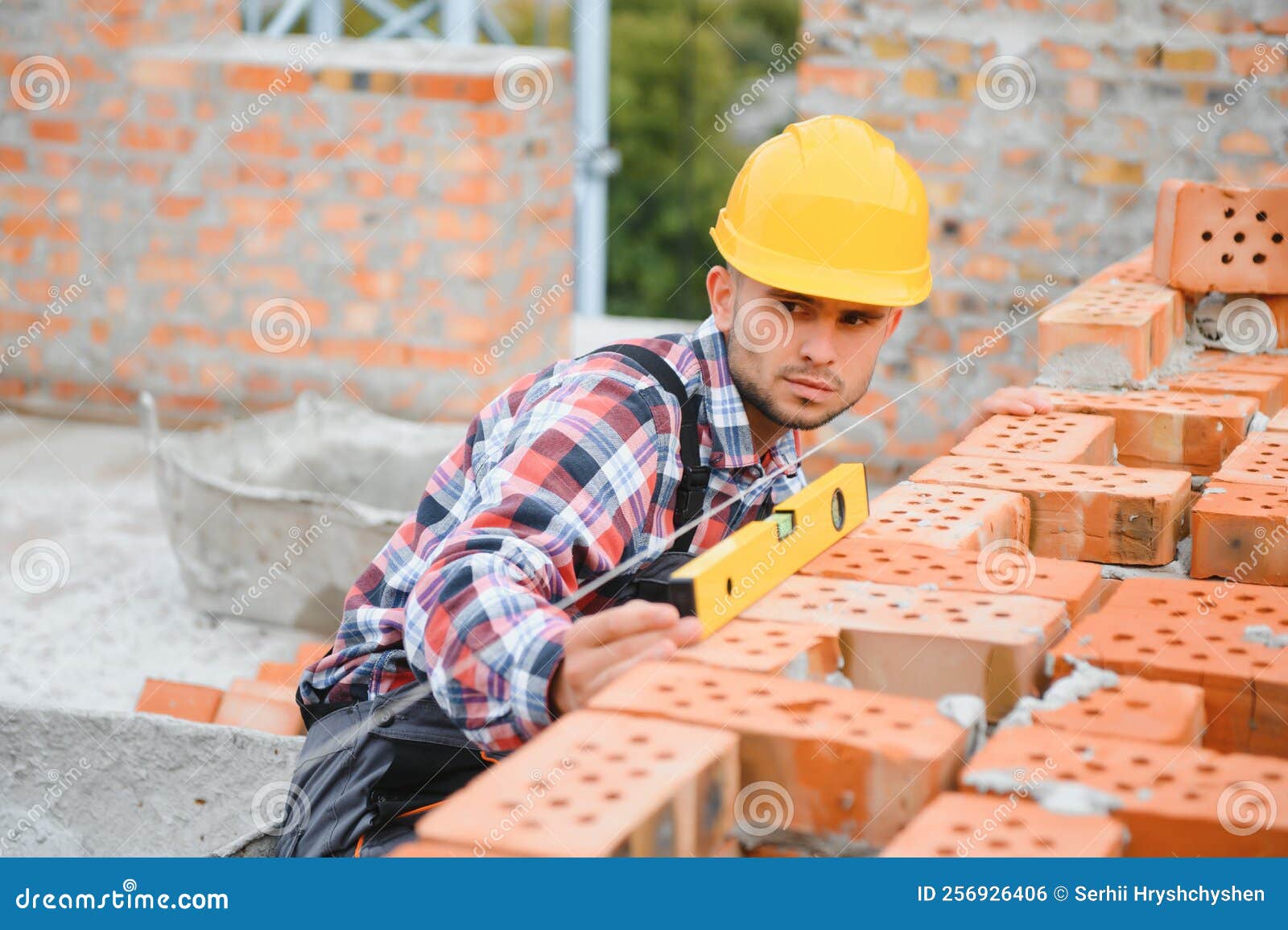 Using Bricks. Young Construction Worker in Uniform is Busy at the ...