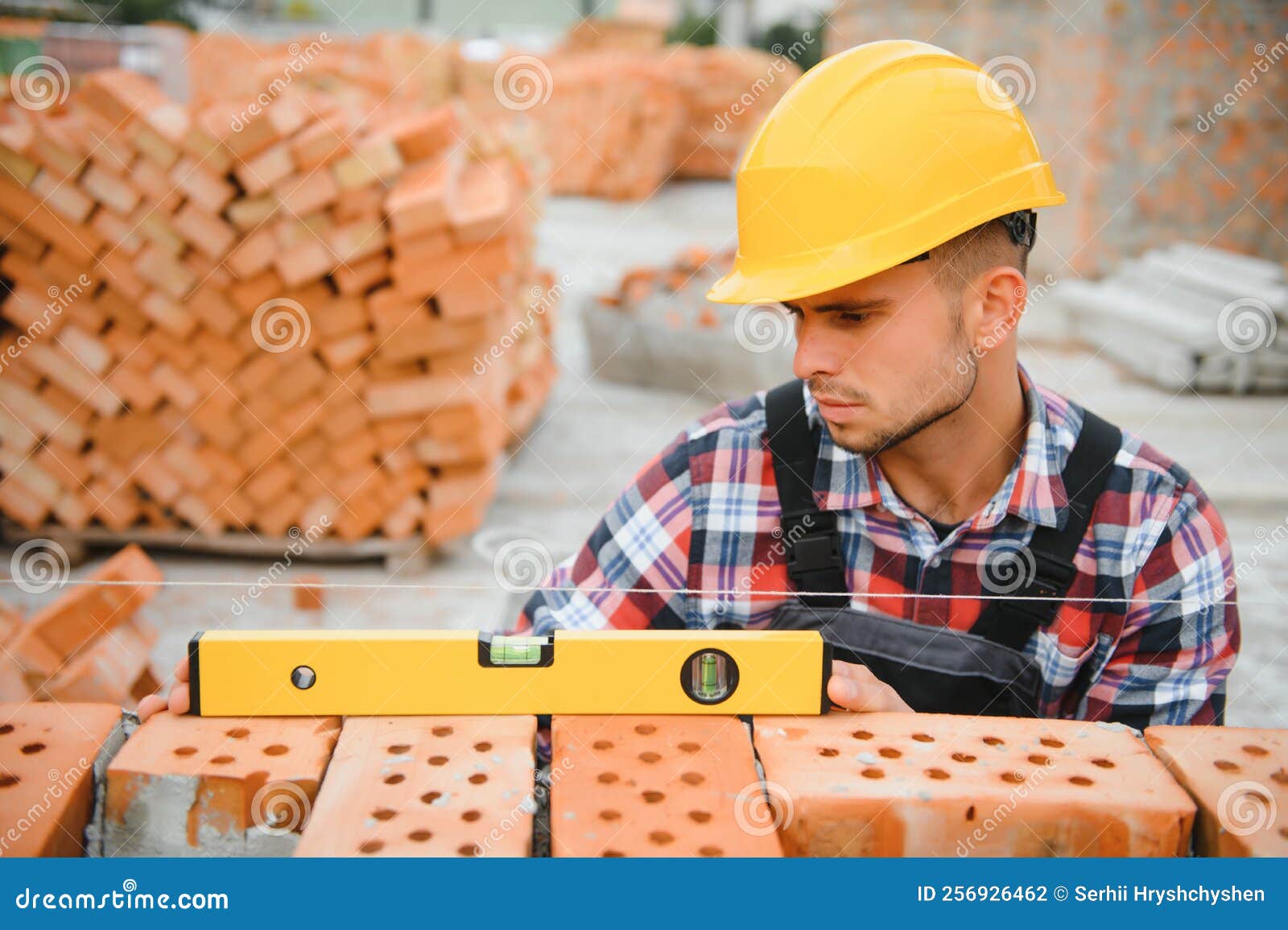 Using Bricks. Young Construction Worker in Uniform is Busy at the ...