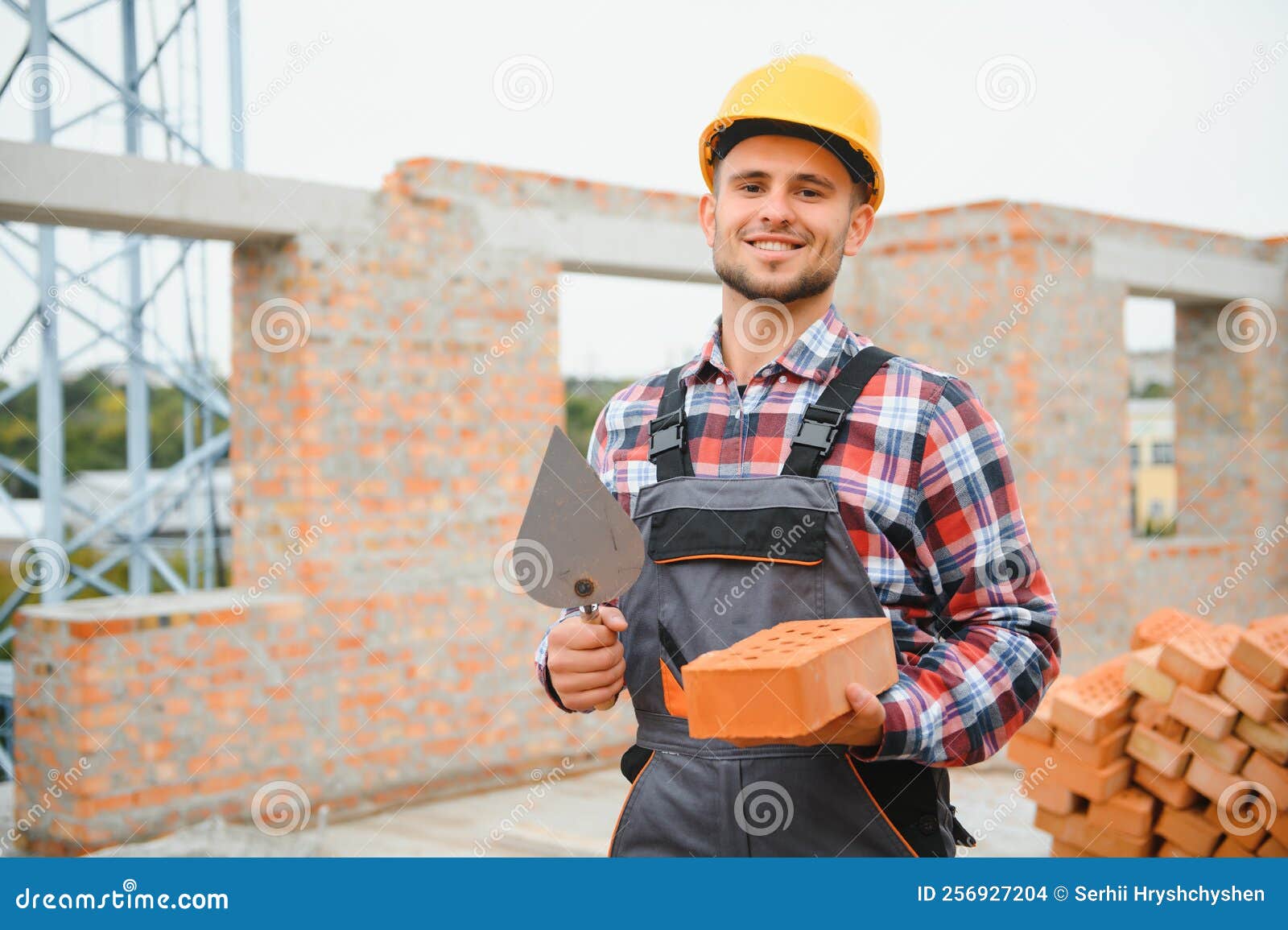 Using Bricks. Young Construction Worker in Uniform is Busy at the ...