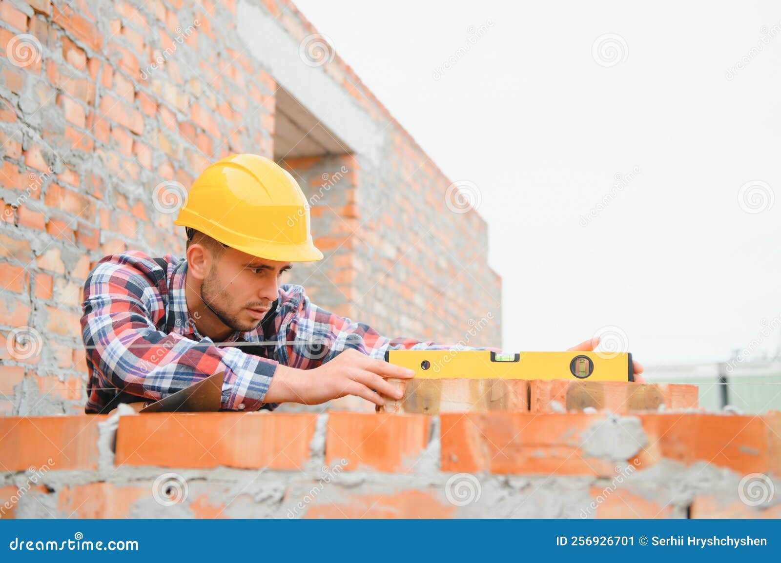 Using Bricks. Young Construction Worker in Uniform is Busy at the ...