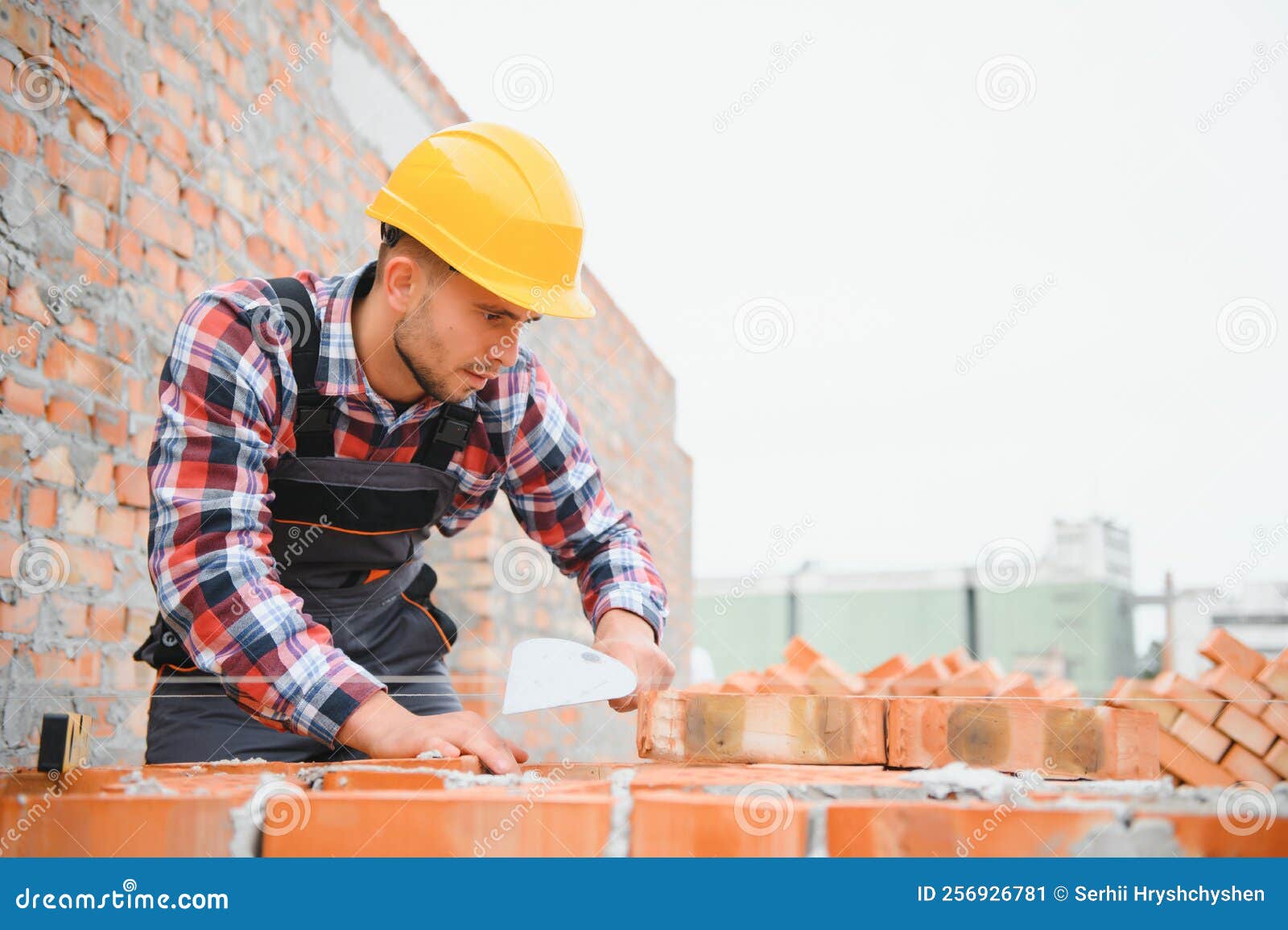 Using Bricks. Young Construction Worker in Uniform is Busy at the ...