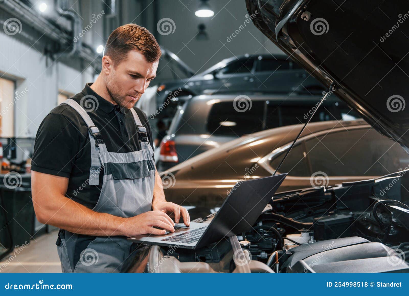 Using Laptop. Man in Uniform is Working in the Auto Service Stock Photo ...