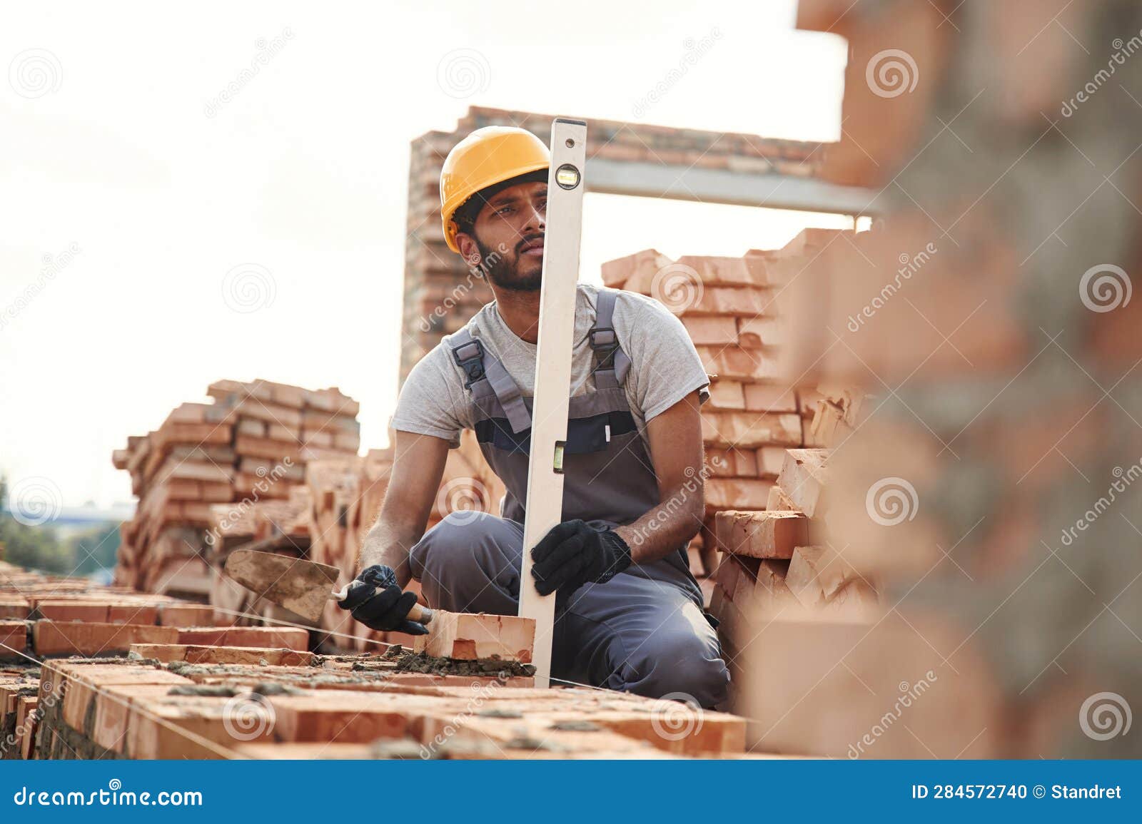 Showing and Holding Little Shovel and Brick. Handsome Indian Man is on ...