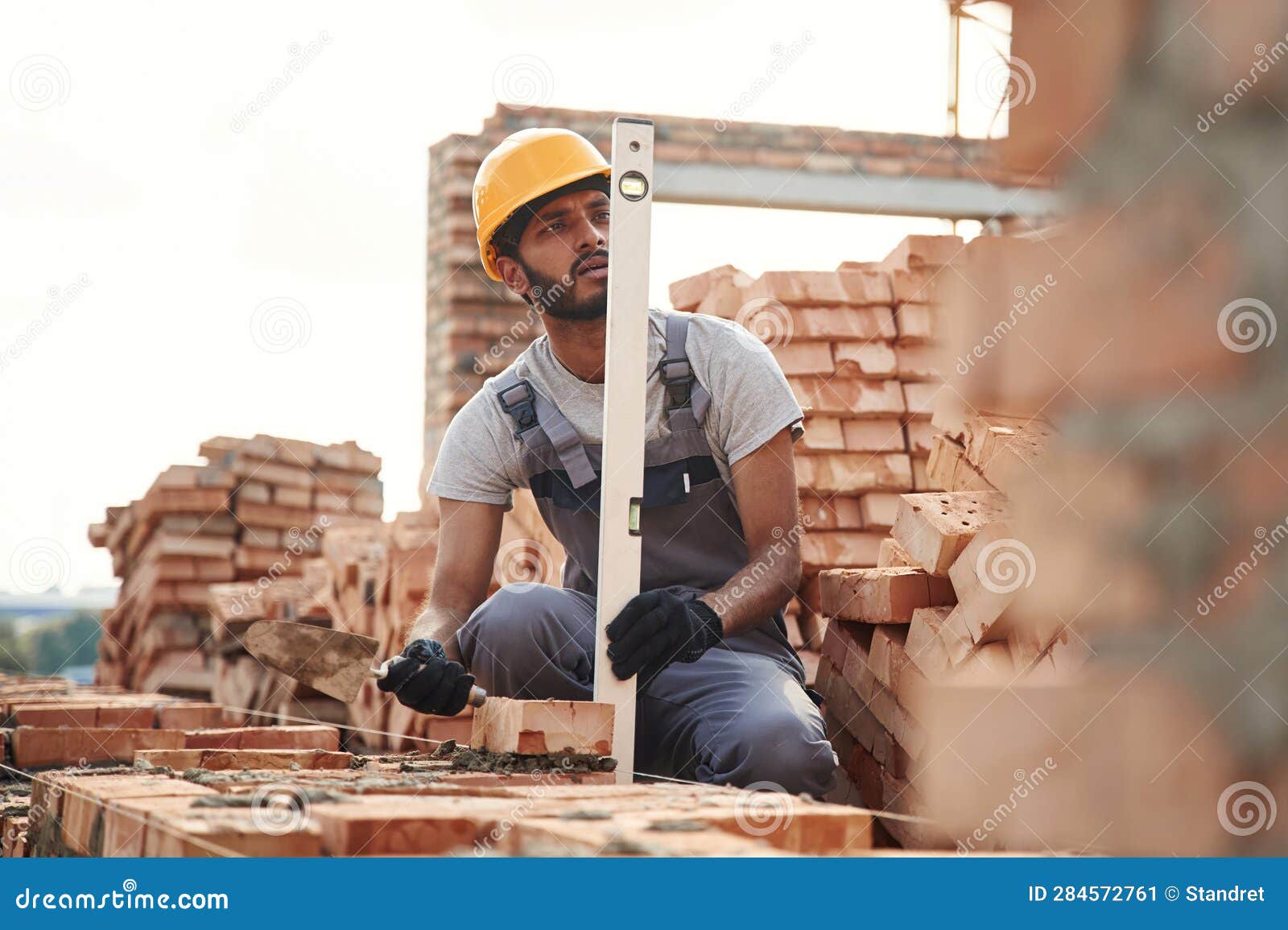 Showing and Holding Little Shovel and Brick. Handsome Indian Man is on ...