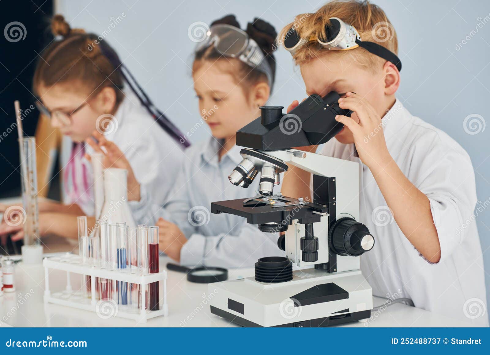 Using Microscope. Children in White Coats Plays a Scientists in Lab by ... Using Microscope. Children in White Coats Plays a Scientists in Lab by ...