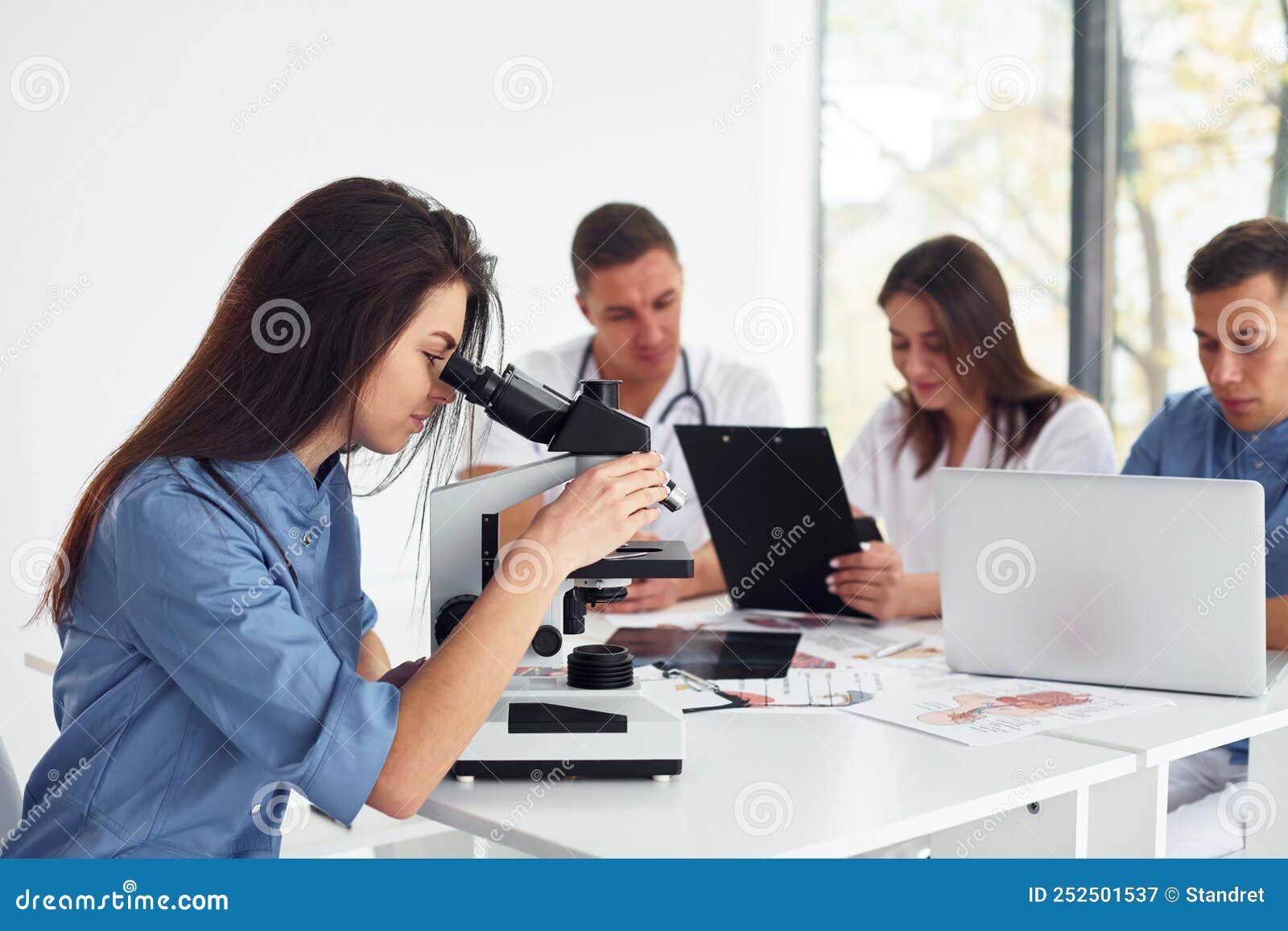 Using Microscope. Group of Young Doctors is Working Together in the ...