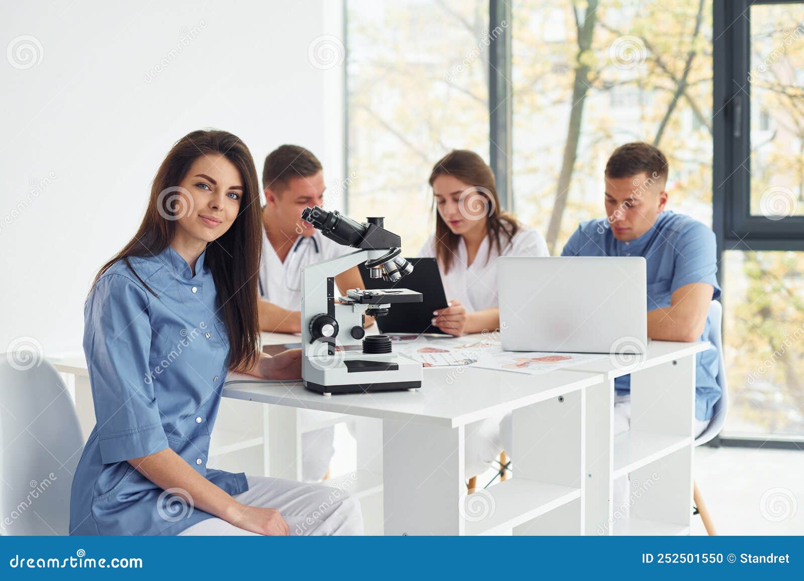 Using Microscope. Group of Young Doctors is Working Together in the ...