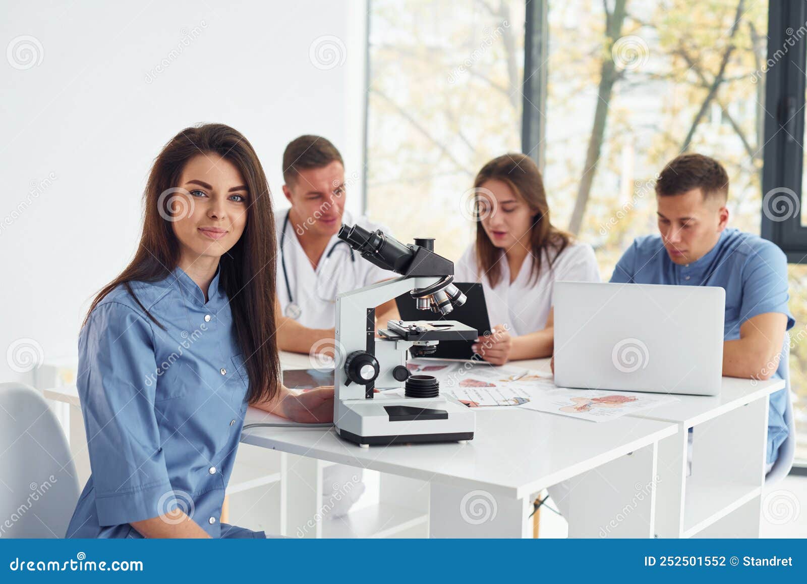 Using Microscope. Group of Young Doctors is Working Together in the ...