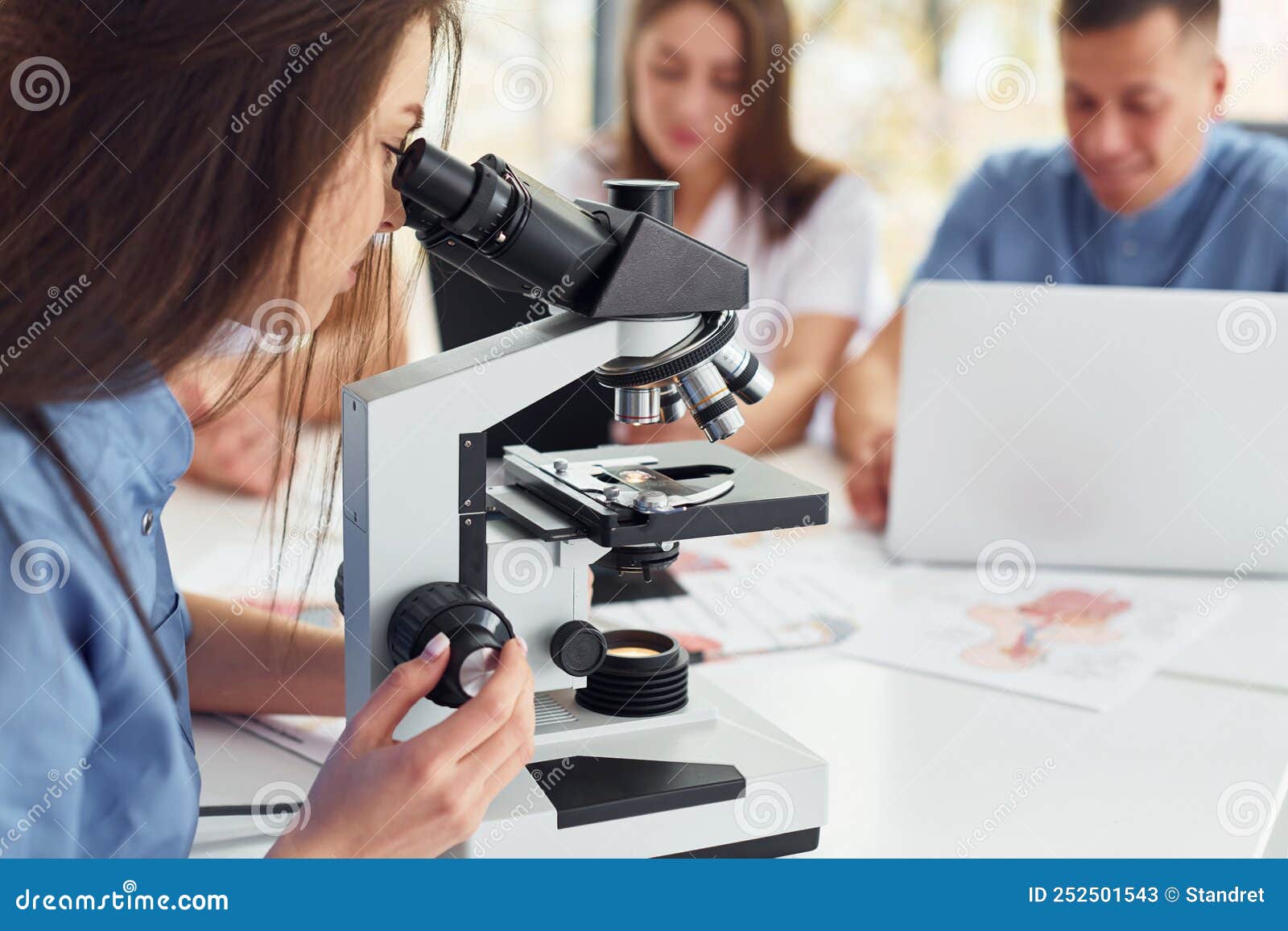 Using Microscope. Group of Young Doctors is Working Together in the ...
