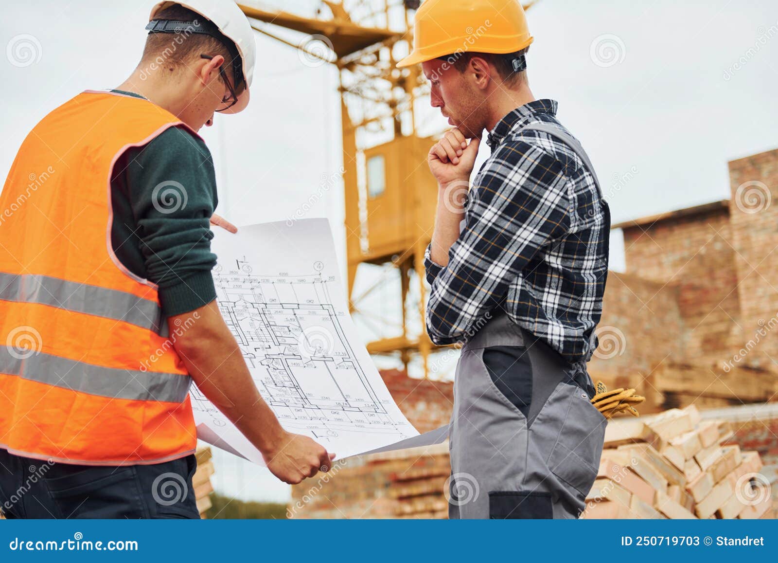 Using Paper Document with Plan on it. Two Construction Workers in ...