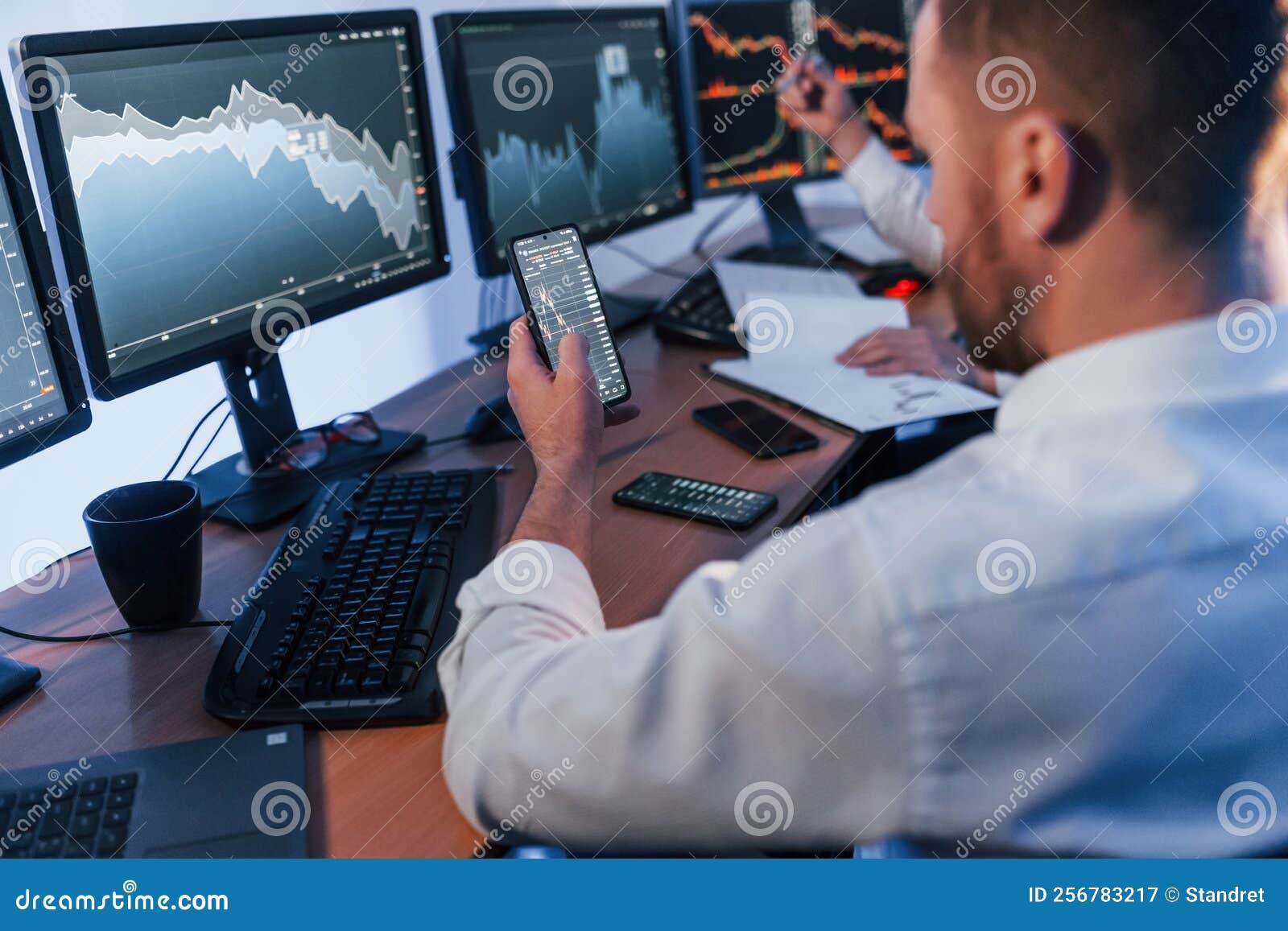 Using the Phone. Two Stock Traders Working in the Office with Exchange ...