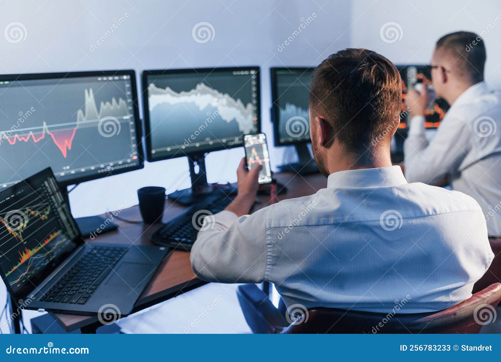 Using the Phone. Two Stock Traders Working in the Office with Exchange ...