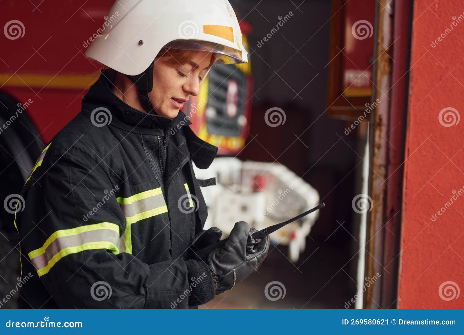 Using Radio Transmitter. Woman Firefighter in Uniform is at Work in ...