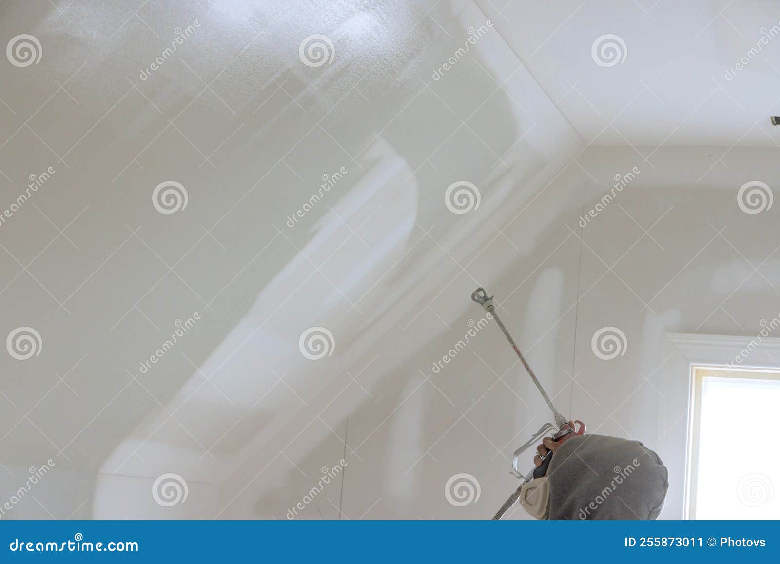 Using a Spray Gun and a Primer, the Worker Paints the Walls and ...