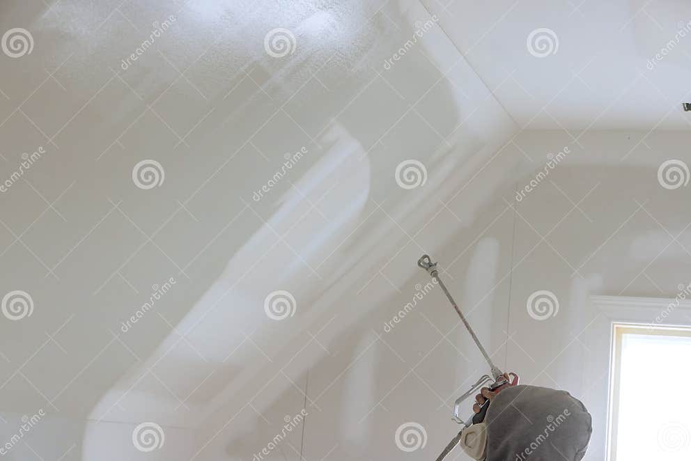 Using a Spray Gun and a Primer, the Worker Paints the Walls and ...