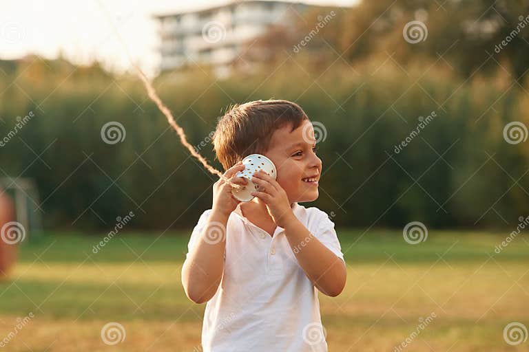 Using String Can Phone. Little Boy is Playing Outdoors at Daytime Stock ...