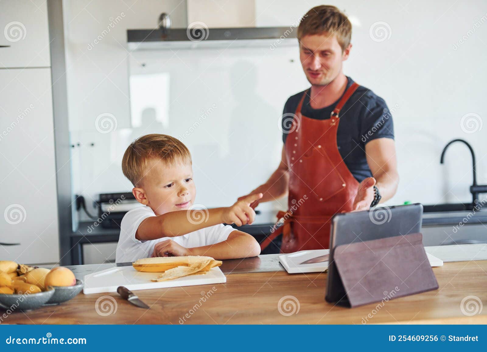 Using Tablet To Learn How To Cook. Father and Son is Indoors at Home ...